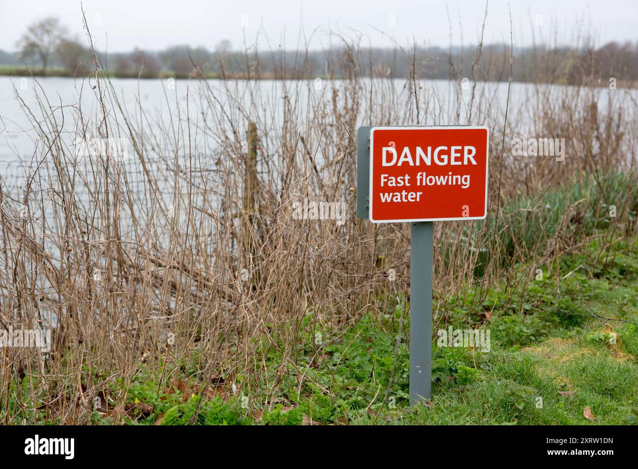 A red warning sign on a post by a fast flowing river Stock Photo - Alamy