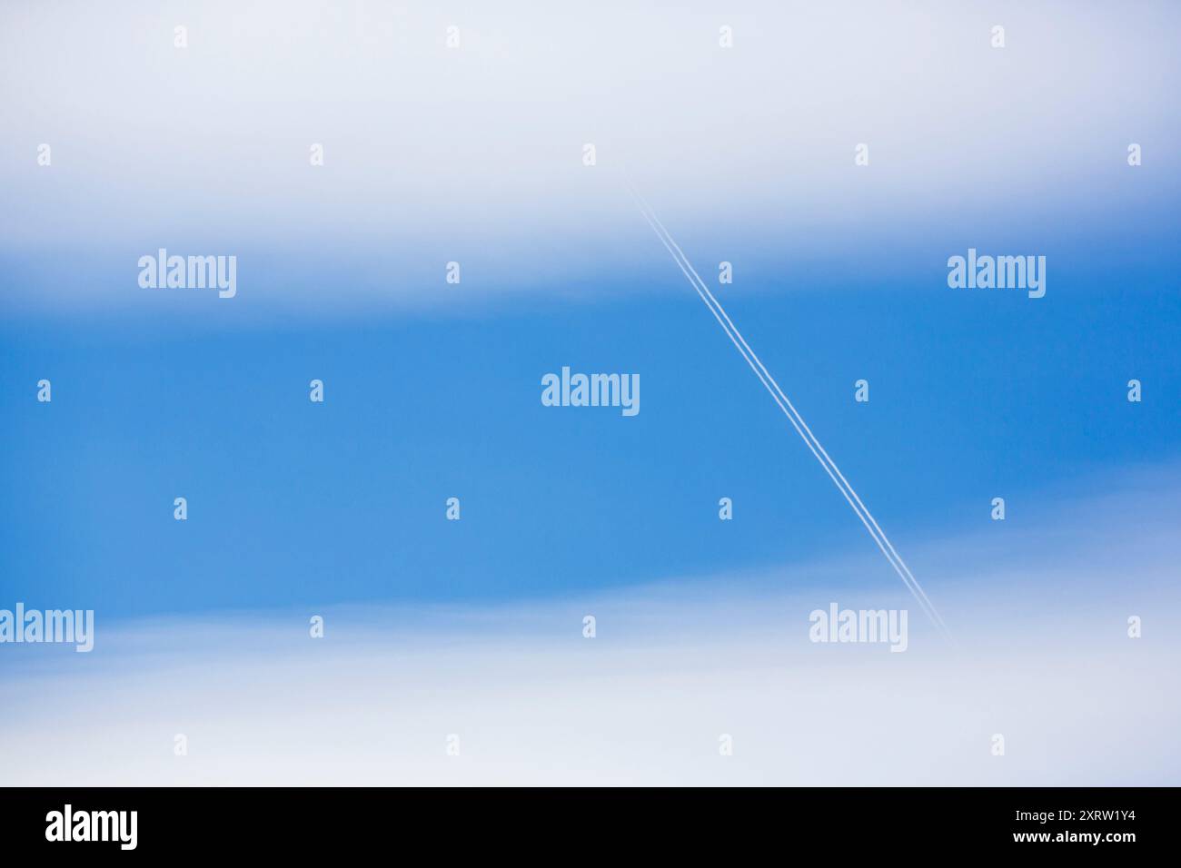 A line of vapor left by a passing jet aircraft as a trail between 2 ...