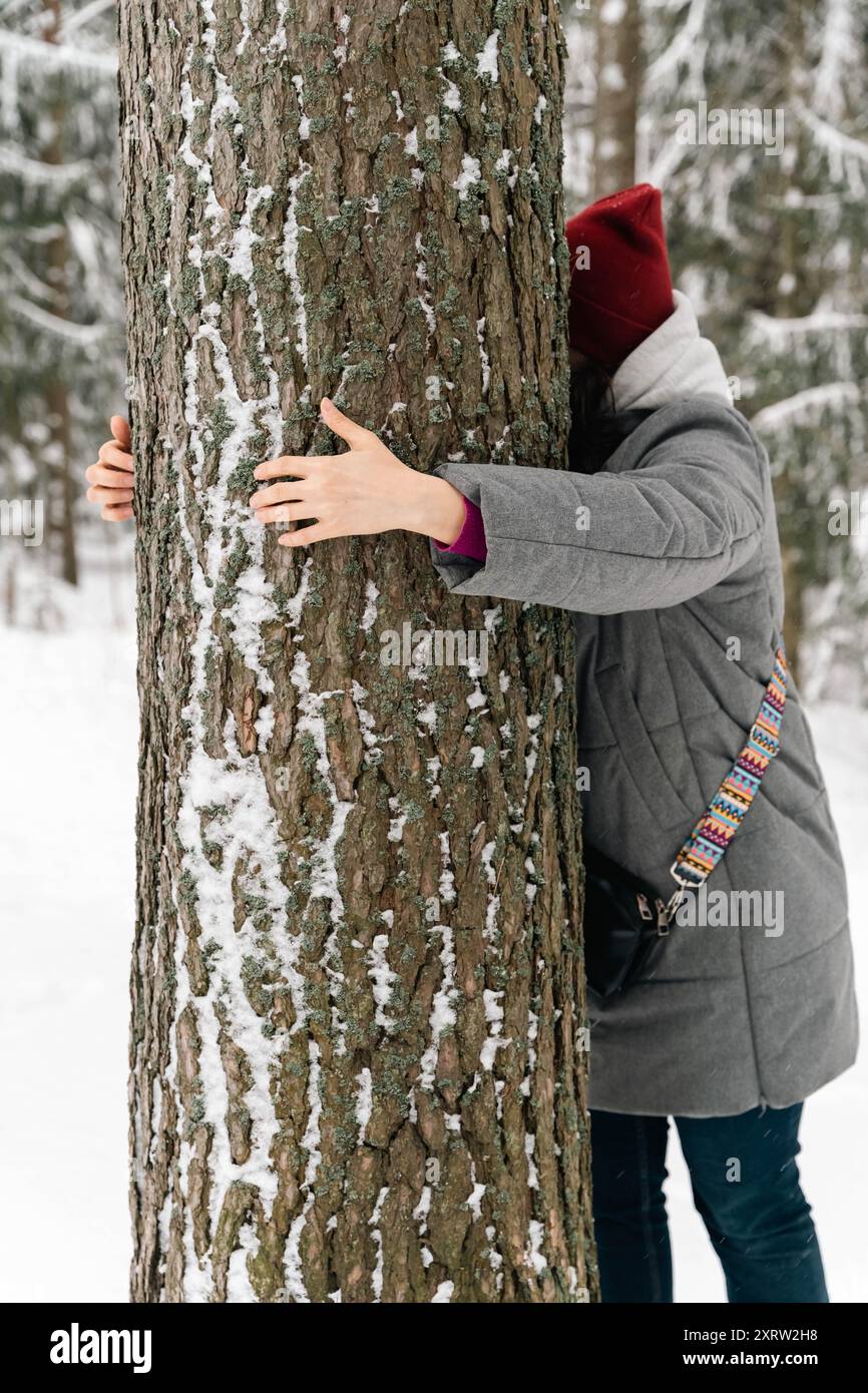 Woman embracing tree in snowy forest, showing love for nature and Earth ...