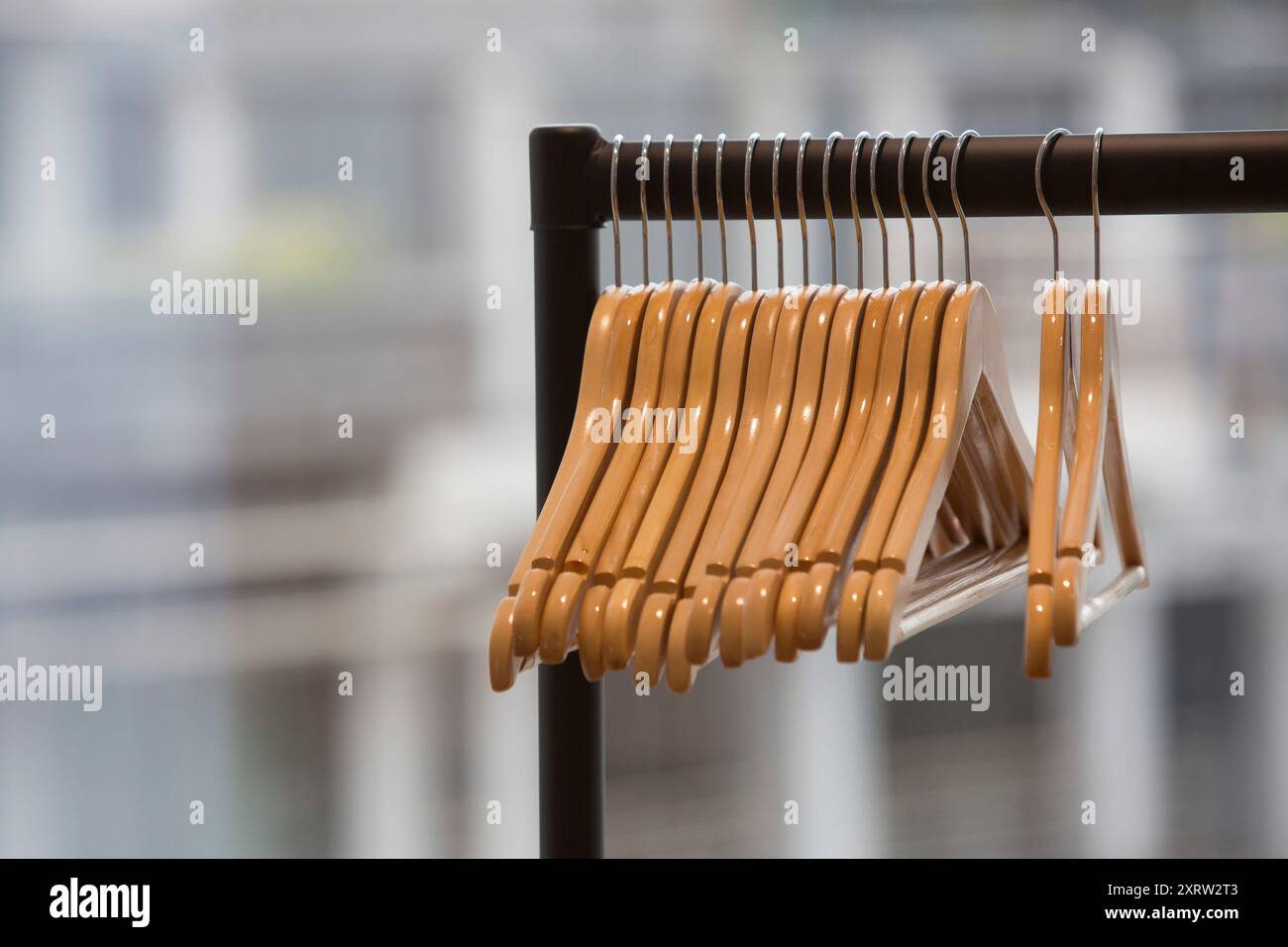 Empty wooden coat hangers, hanging from a rail Stock Photo - Alamy