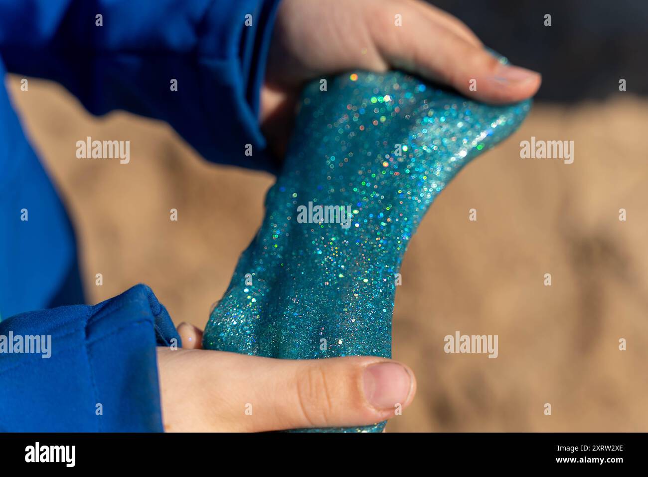 A person holds a green object, likely slime, in their hand Stock Photo ...