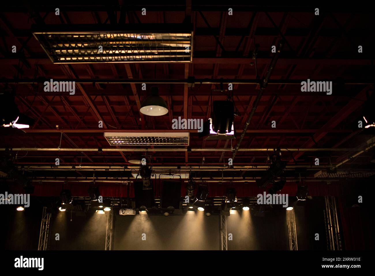 A theatre stage lit by multicoloured lights, empty in preperation for a ...