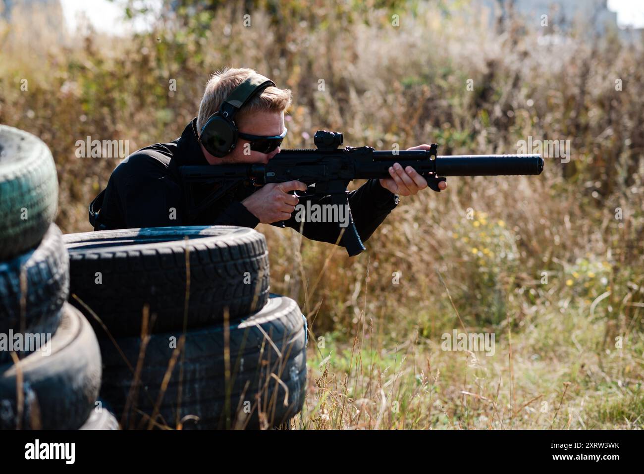 A guy with a machine gun learns to shoot at a shooting range on a sunny ...