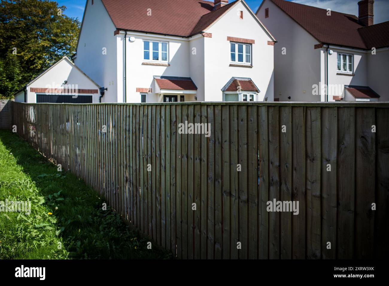 White painted houses in the sunshine behind a long wooden fence Stock ...