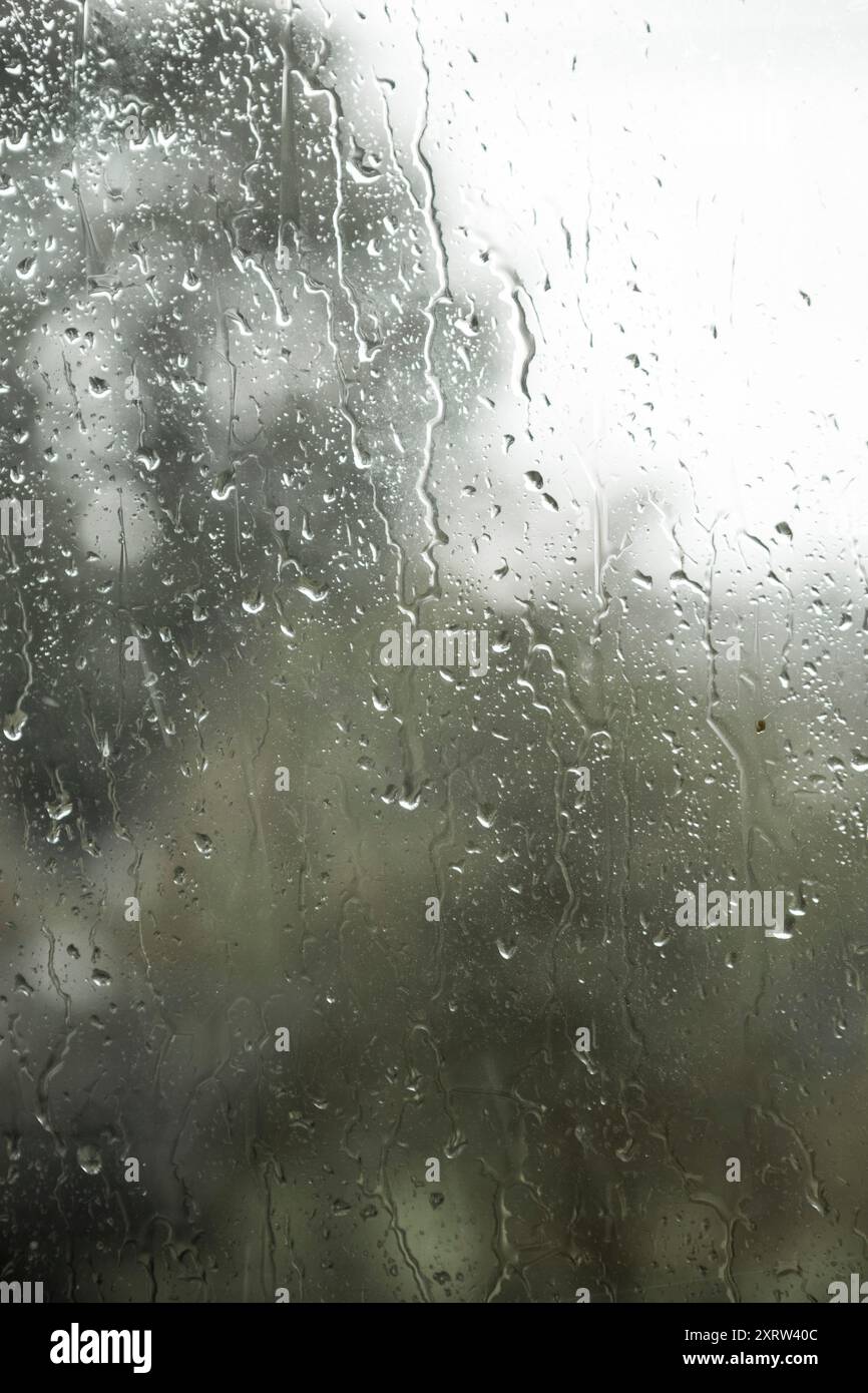 A heavy downpour sends rivulets and drops of rain running down a window Stock Photo - Alamy