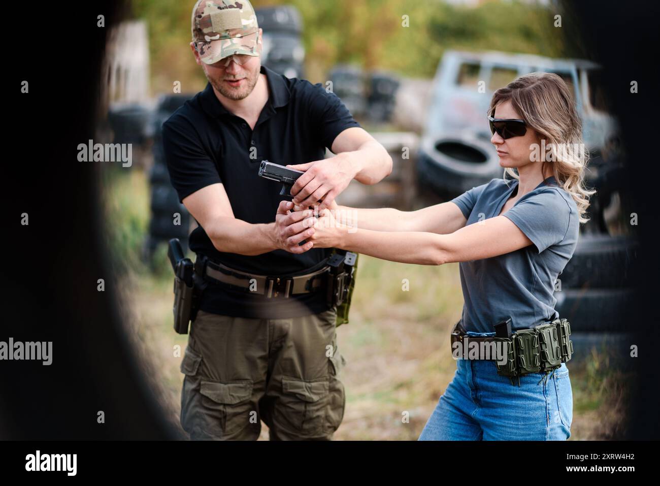 A woman learns to shoot a pistol at a shooting range with an instructor ...