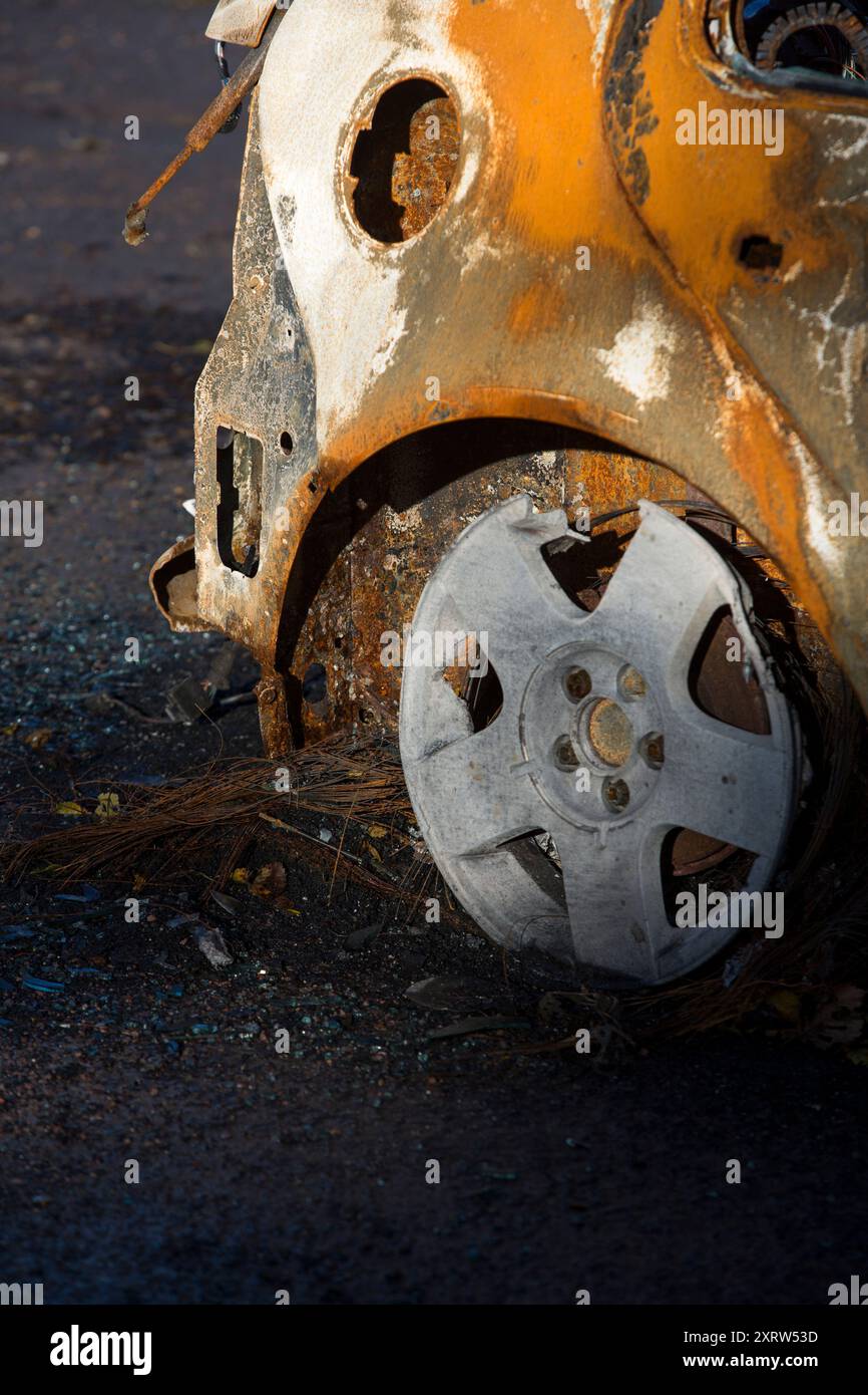 The burnt out wreck of a car on the roadside, destroyed by fire, with ...