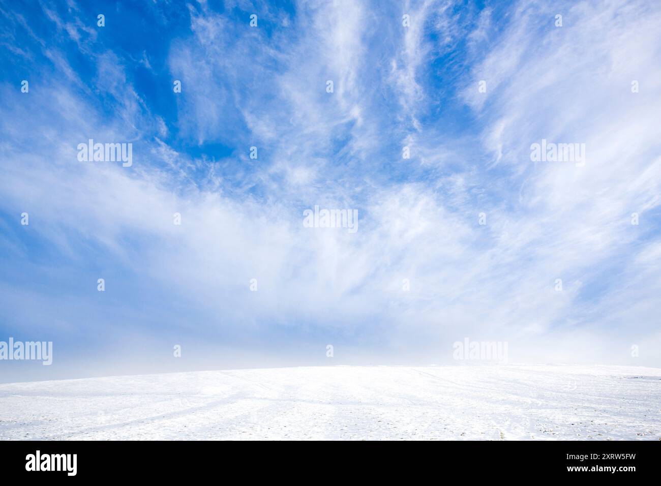 An empty snow covered landscape with low hill and deep blue sky, light ...