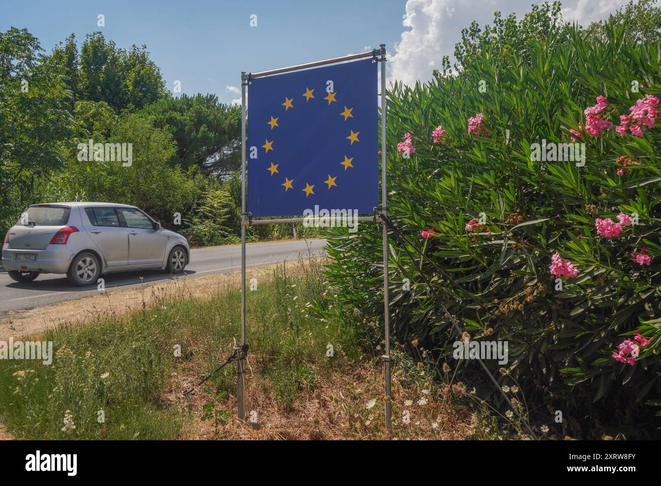 A modern road sign with the European Union Flag on blue sky with clouds ...