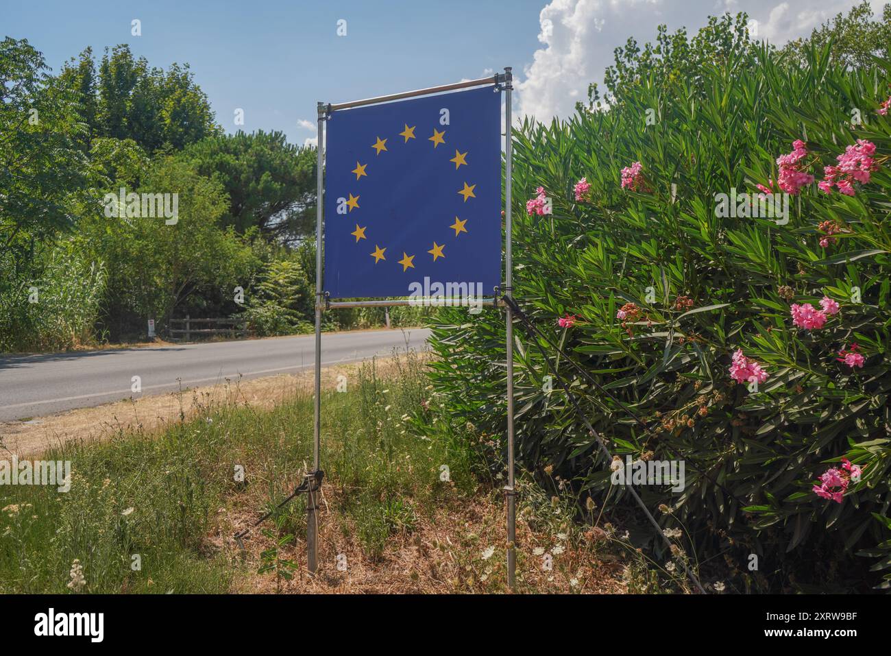 A modern road sign with the European Union Flag on blue sky with clouds ...