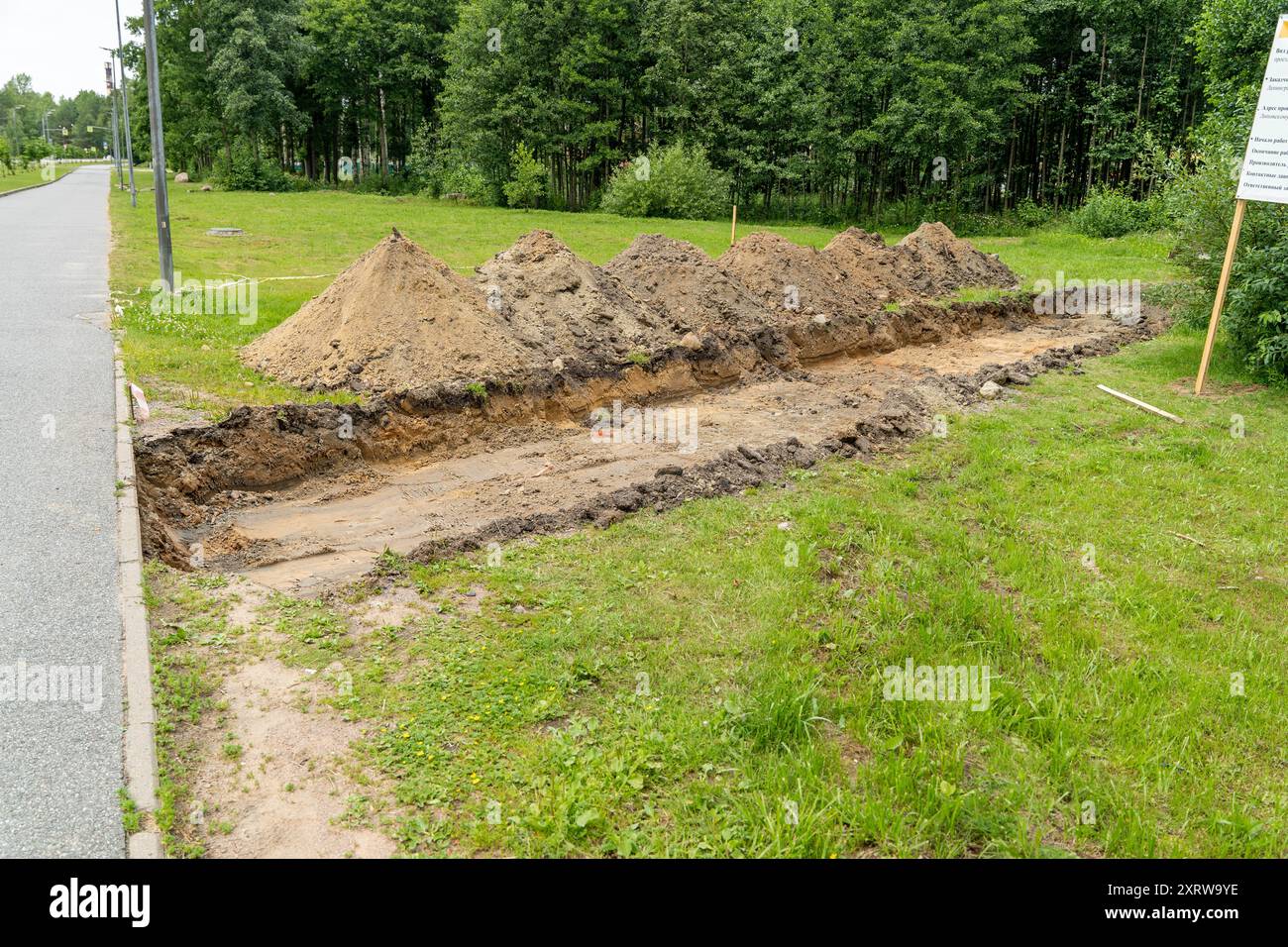 Trench dug in green grass next to a paved road Stock Photo - Alamy