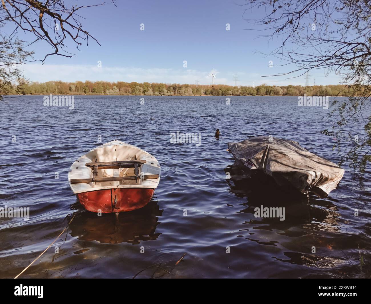 Two boats are floating in a lake, one of which is covered with a tarp ...
