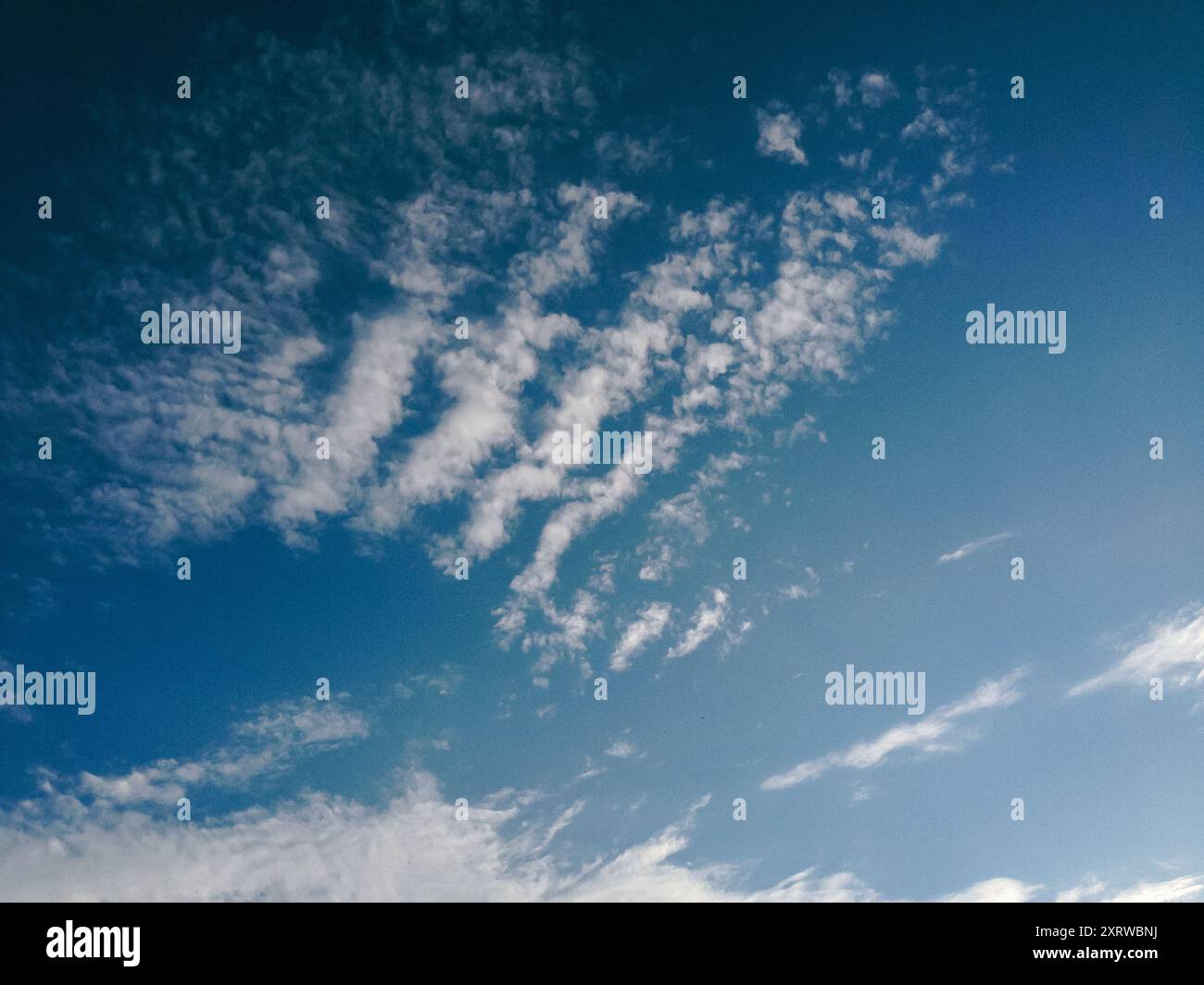 The sky is blue with a few clouds scattered throughout. The clouds are ...