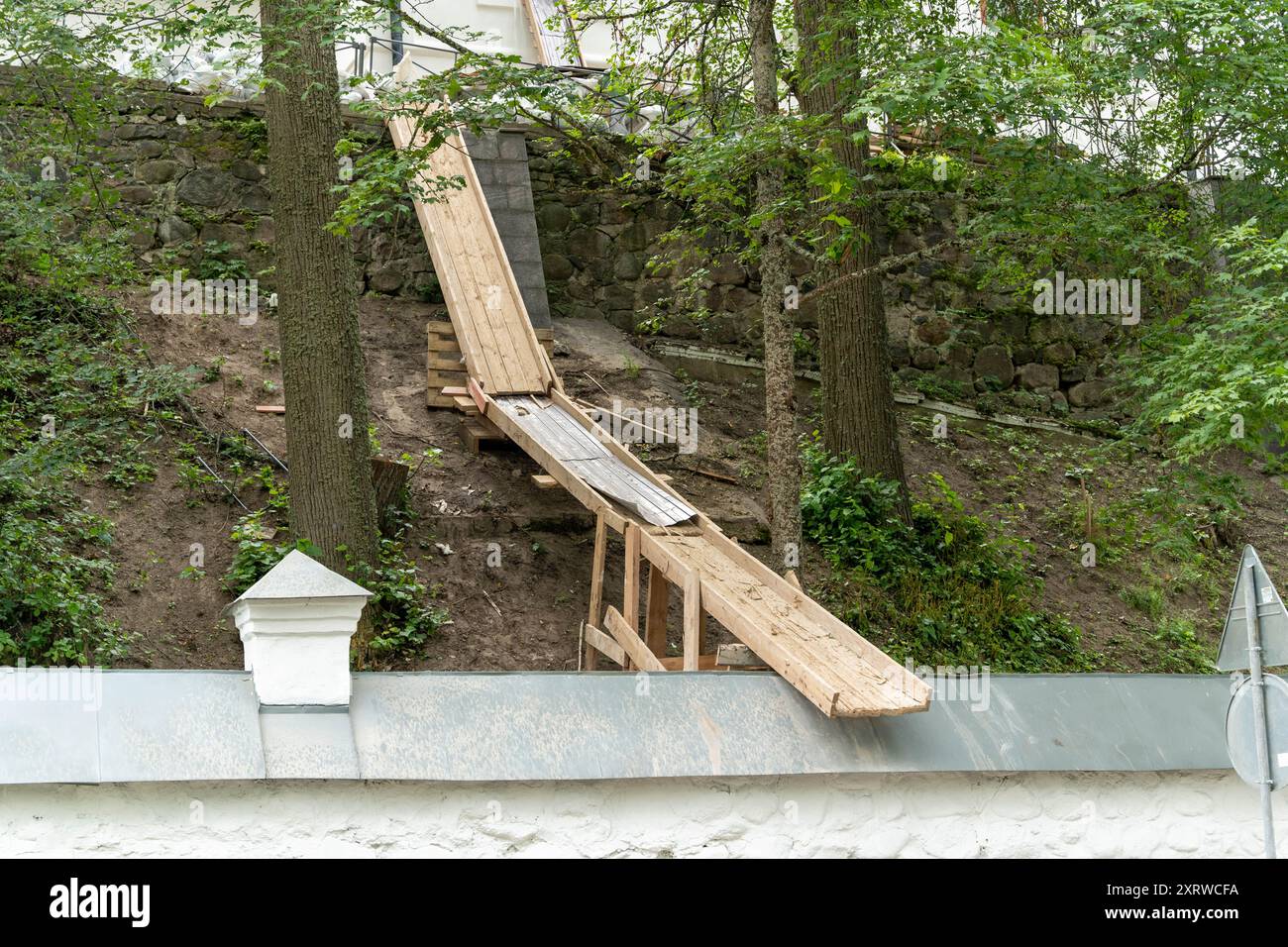 A wooden ramp is built sloping down a hillside among trees Stock Photo ...
