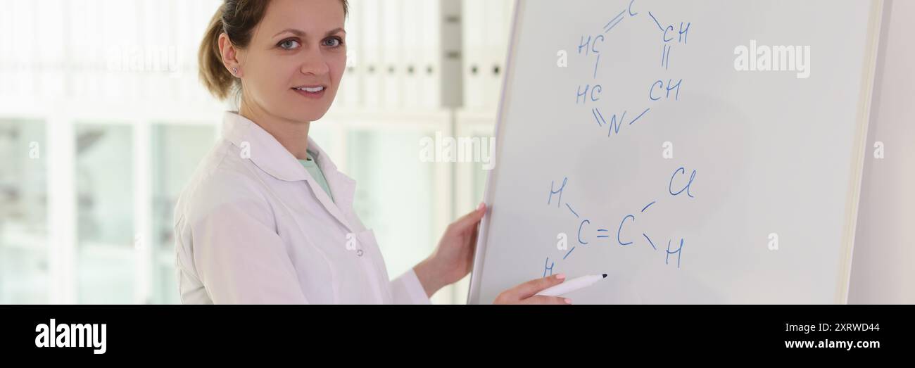 Smiling female scientist drawing chemical formulas on whiteboard Stock ...