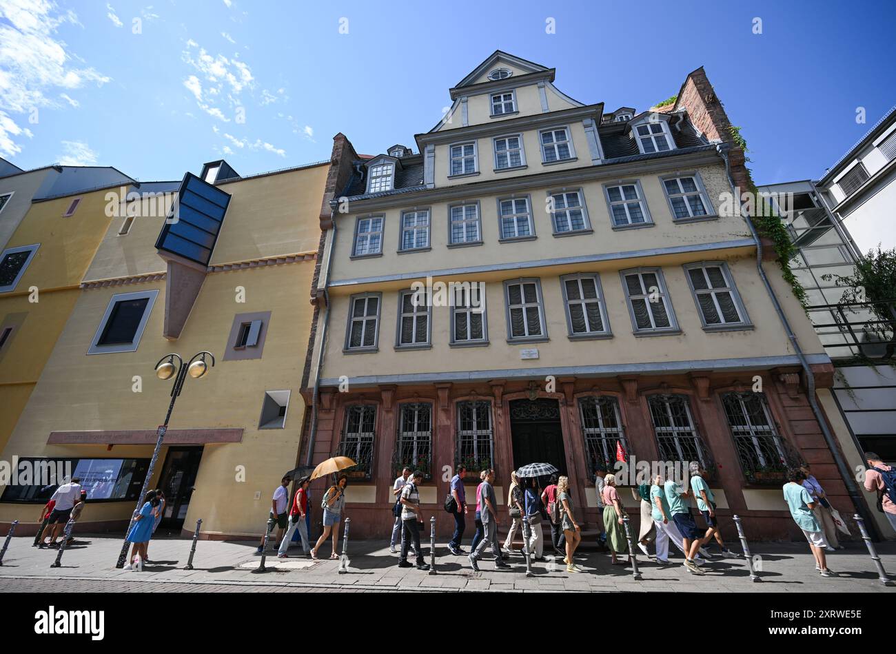 PRODUCTION - 12 August 2024, Hesse, Frankfurt/Main: Tourists walk past ...