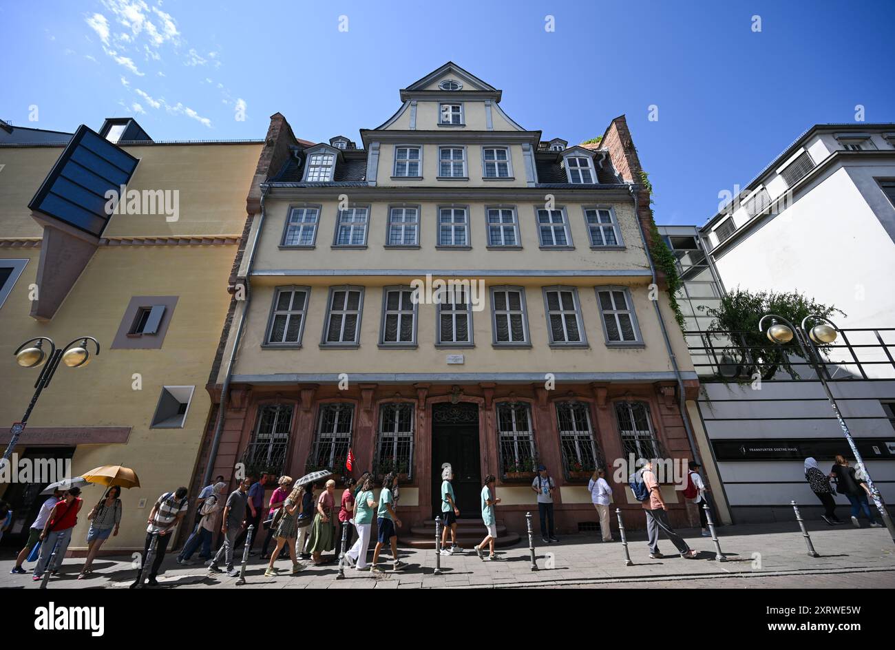 PRODUCTION - 12 August 2024, Hesse, Frankfurt/Main: Tourists walk past ...