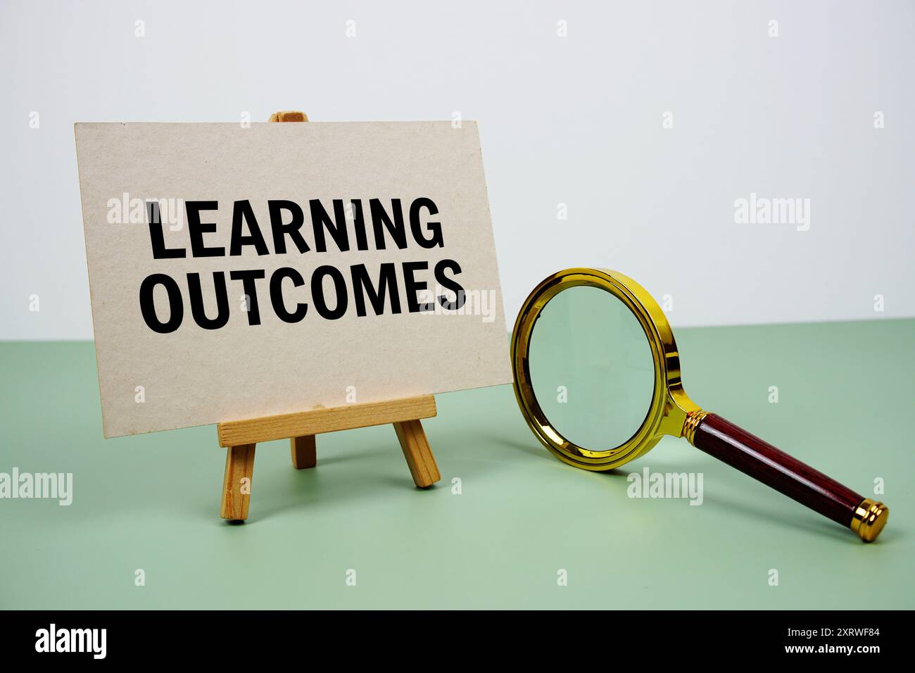 Learning Outcomes text on paper card with magnifying glass on green ...