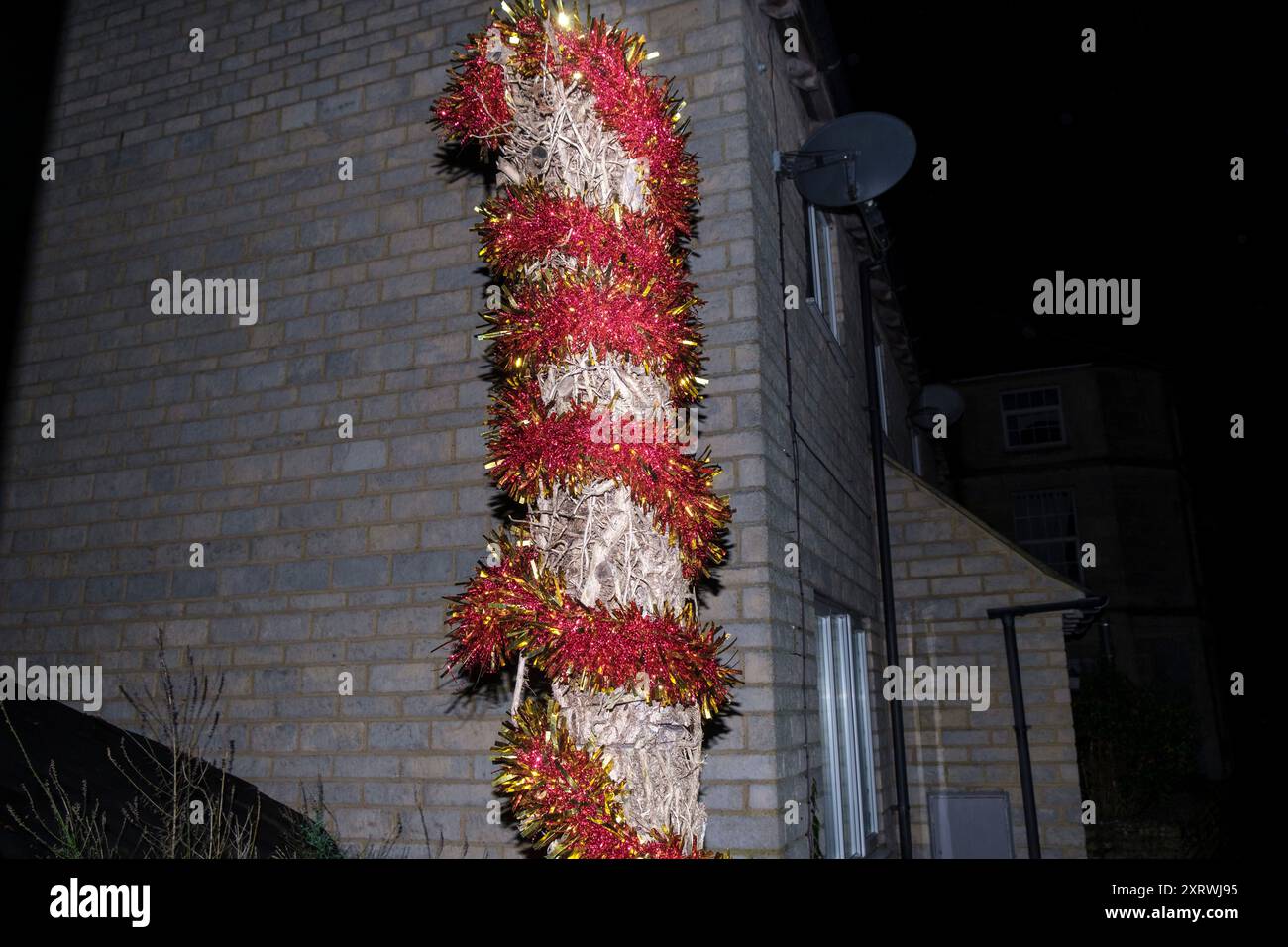 Christmas tinsel wrapped around an old ivy covered post on a street in ...
