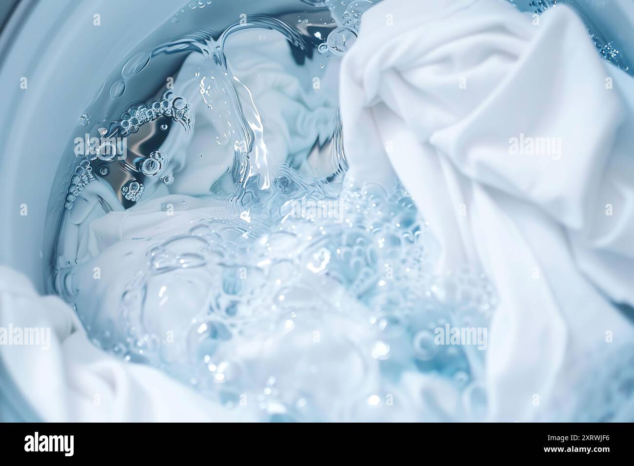 Clothes in washing machine indoors, with detergent water dissolution ...