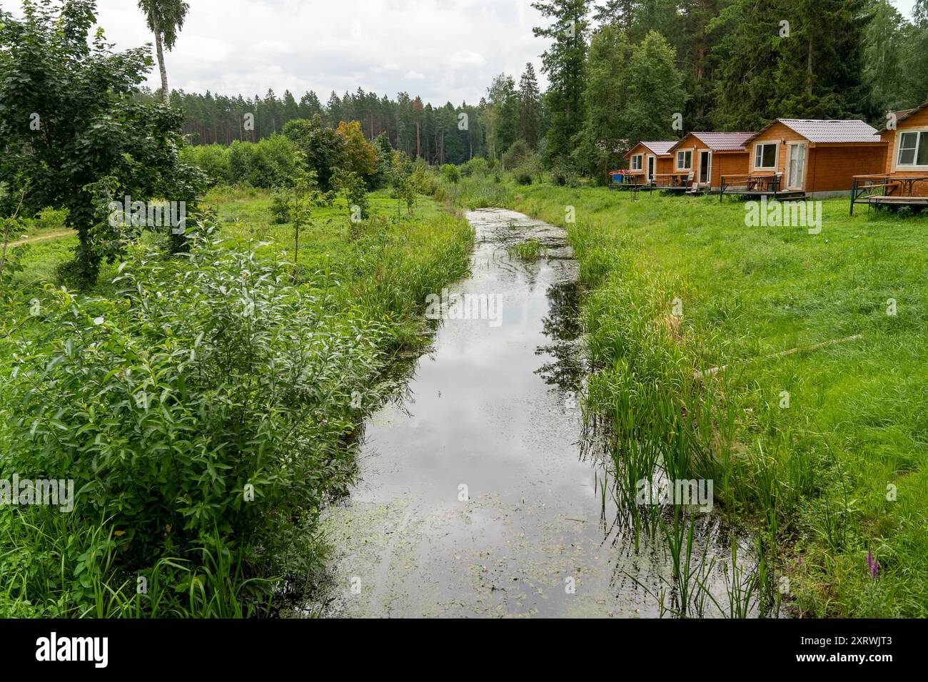 Cabins nestled along a peaceful stream with vibrant foliage Stock Photo ...