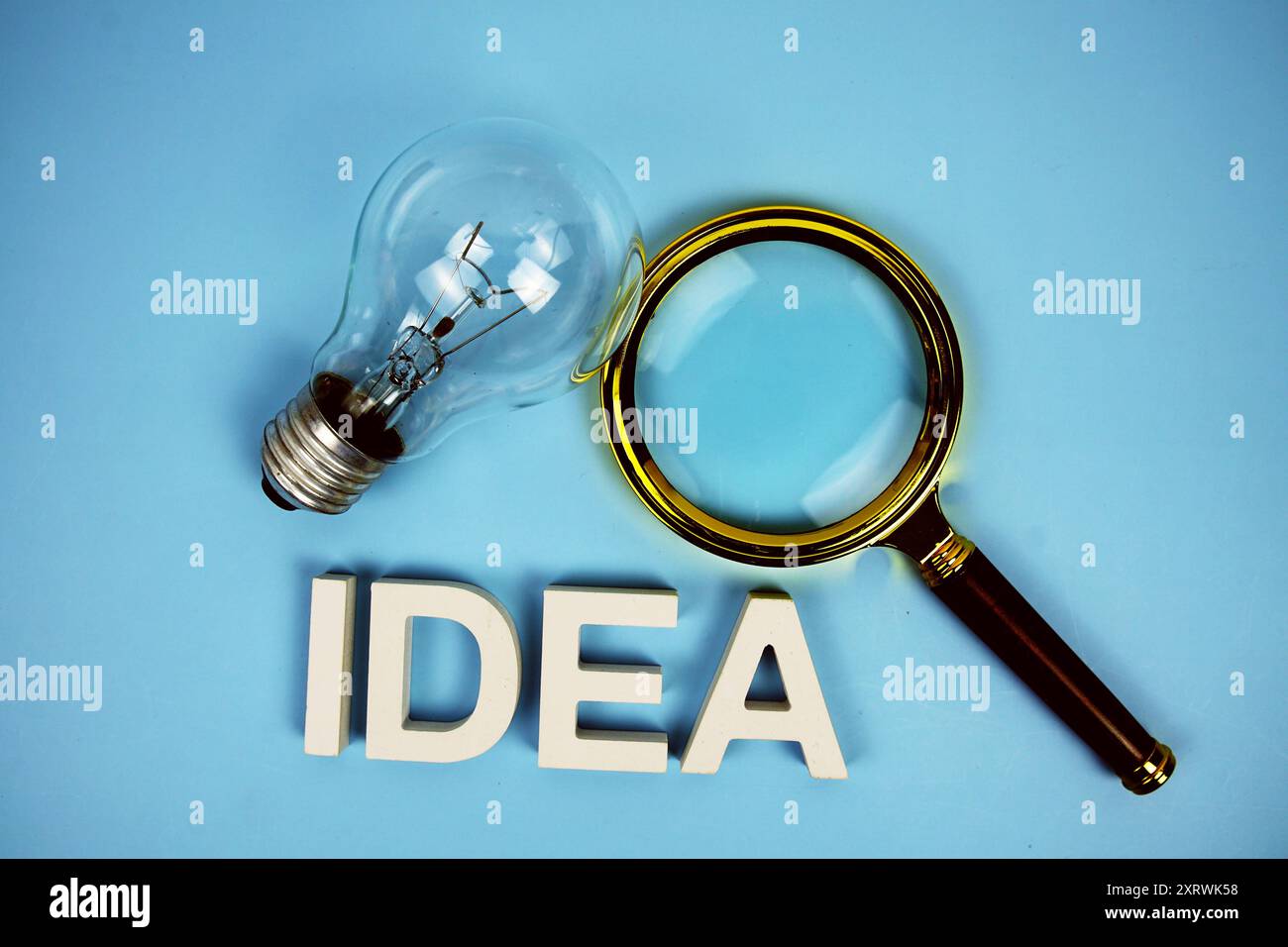 Idea word with light bulb and magnifying glass top view on blue ...