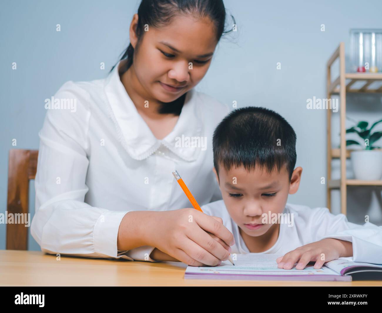 Female tutor helping little elementary school boy with homework during ...