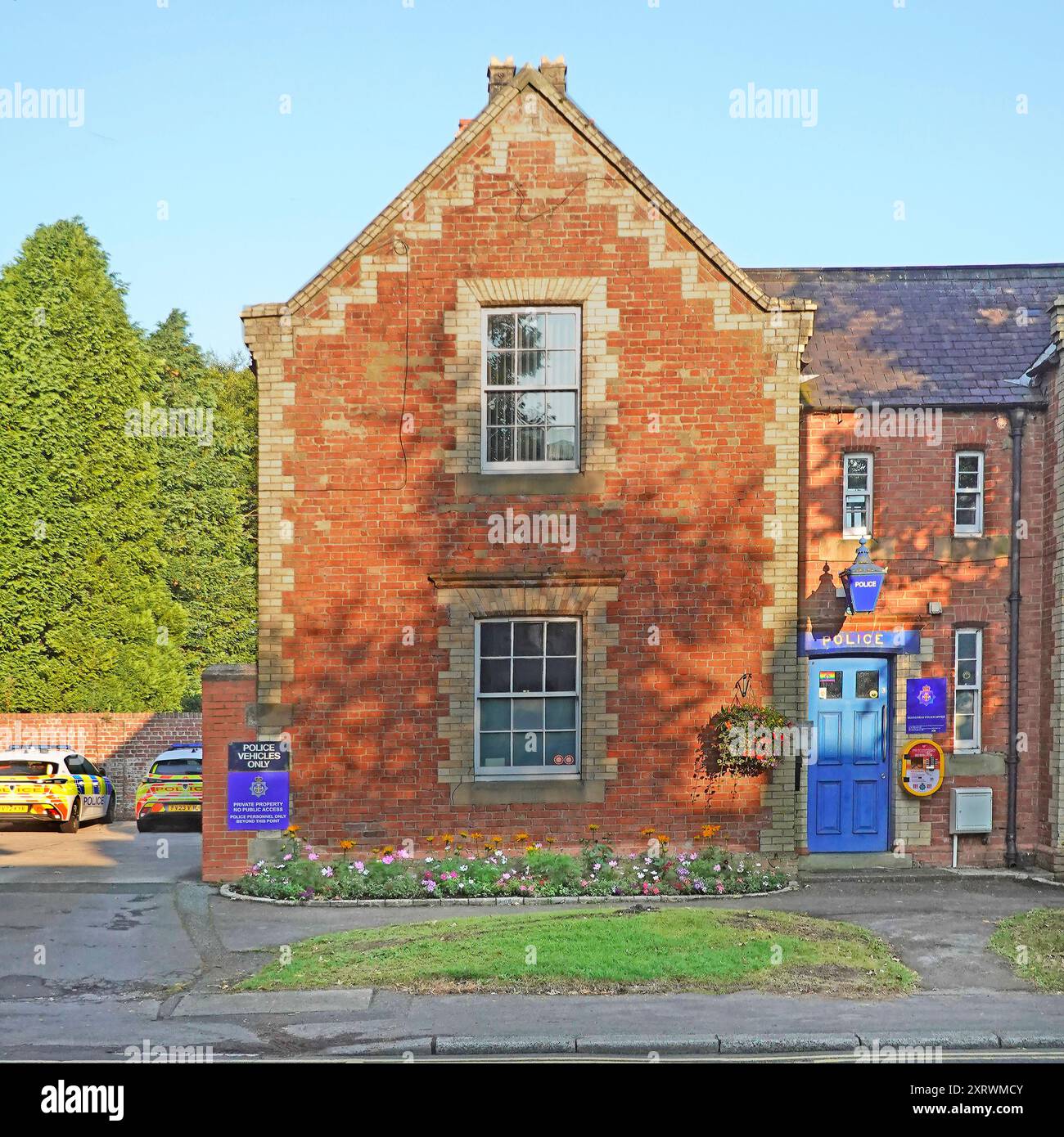 Trees cast shadows on old fashioned brick built traditional blue lamp ...