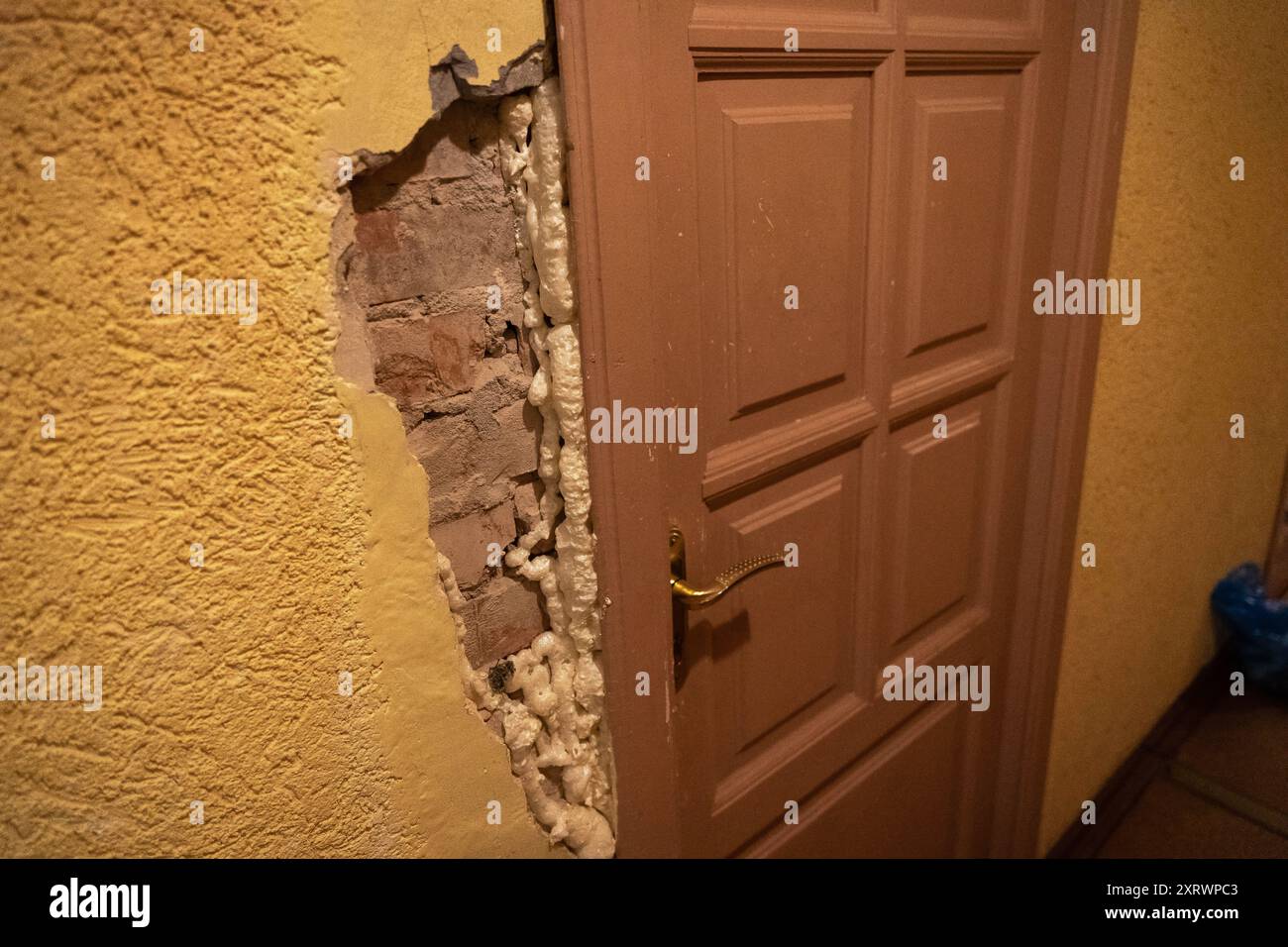 Exposed wall with insulation visible alongside a brown door. destroyed ...