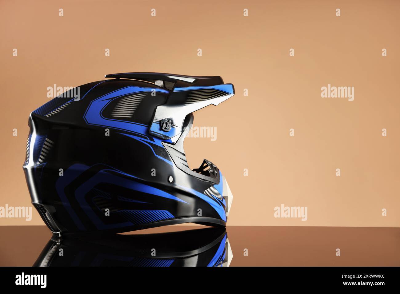 Modern motorcycle helmet with visor on mirror surface against beige ...