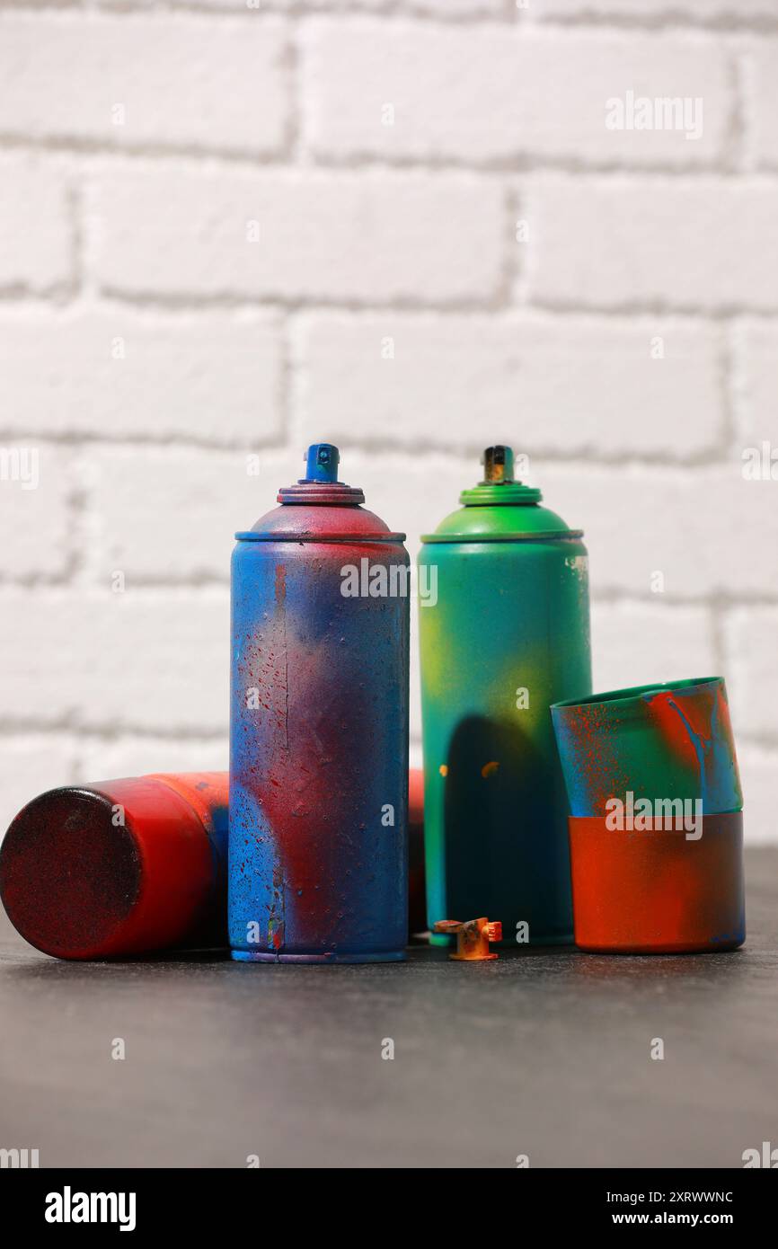 Many spray paint cans on gray surface against white brick wall Stock ...