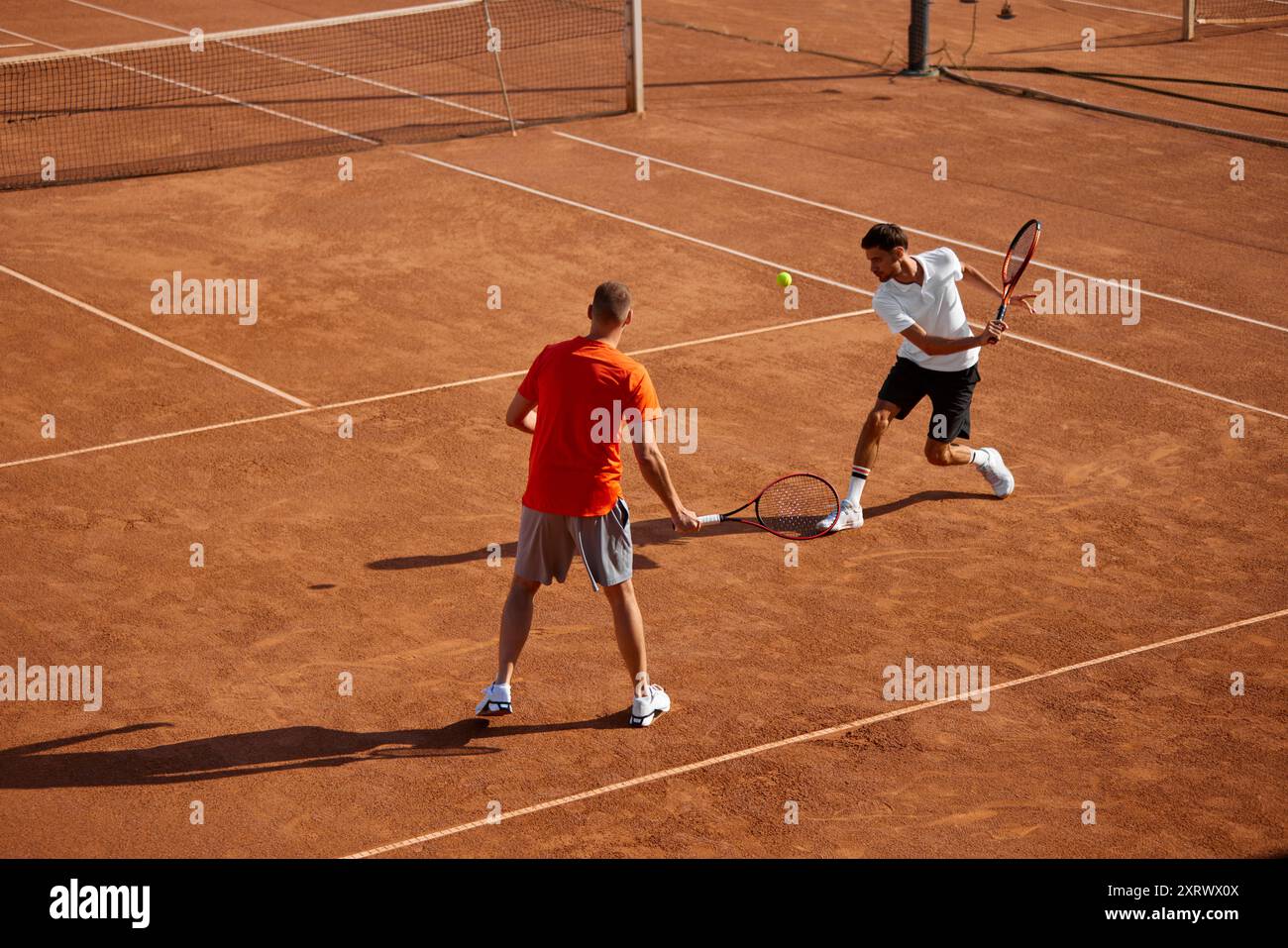 Two men, tennis players in motion on outdoor clay court, showing game ...