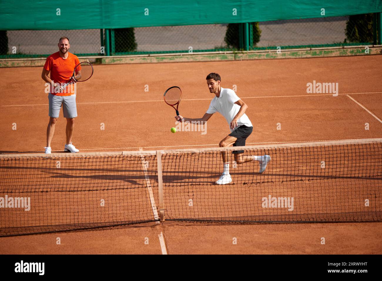 Concentrated men, tennis players in motion on open air clay court ...