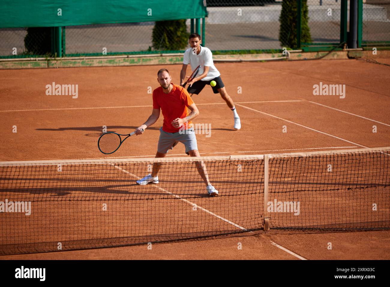 Concentrated men, tennis players in motion on open air clay court ...