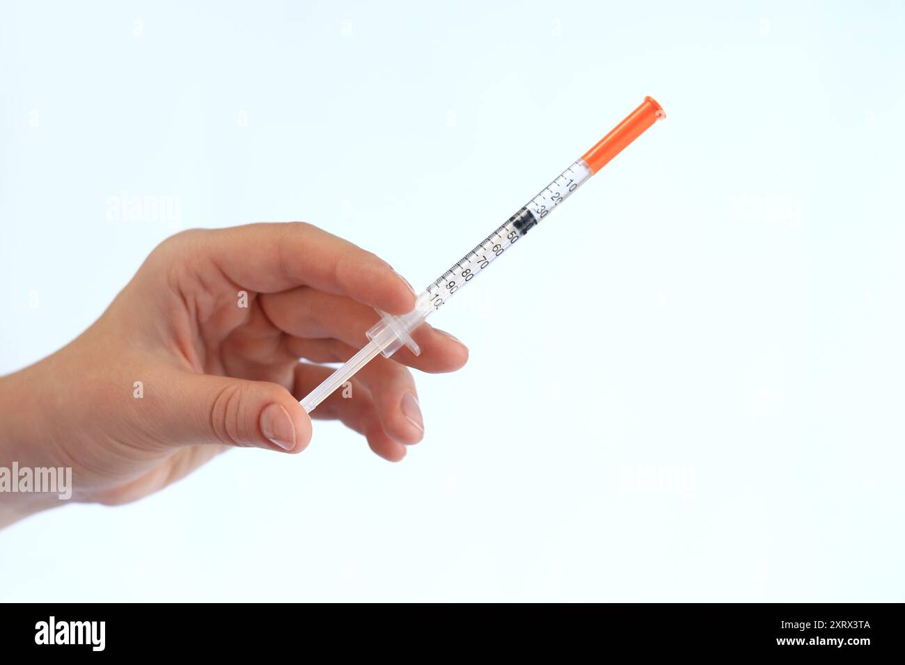 Insulin syringe. A woman's hand holds a syringe on a white background ...