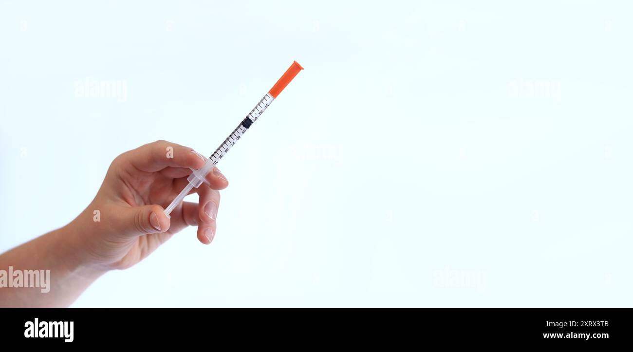 Insulin syringe. A woman's hand holds a syringe on a white background ...