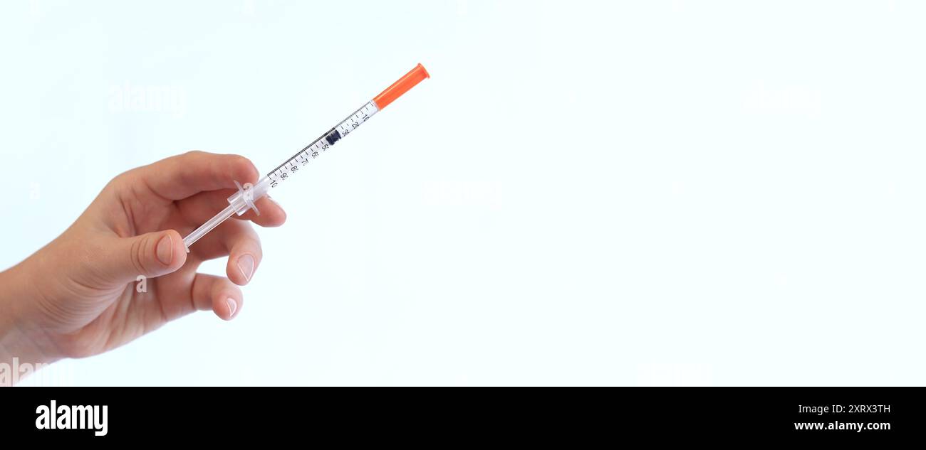 Insulin syringe. A woman's hand holds a syringe on a white background ...