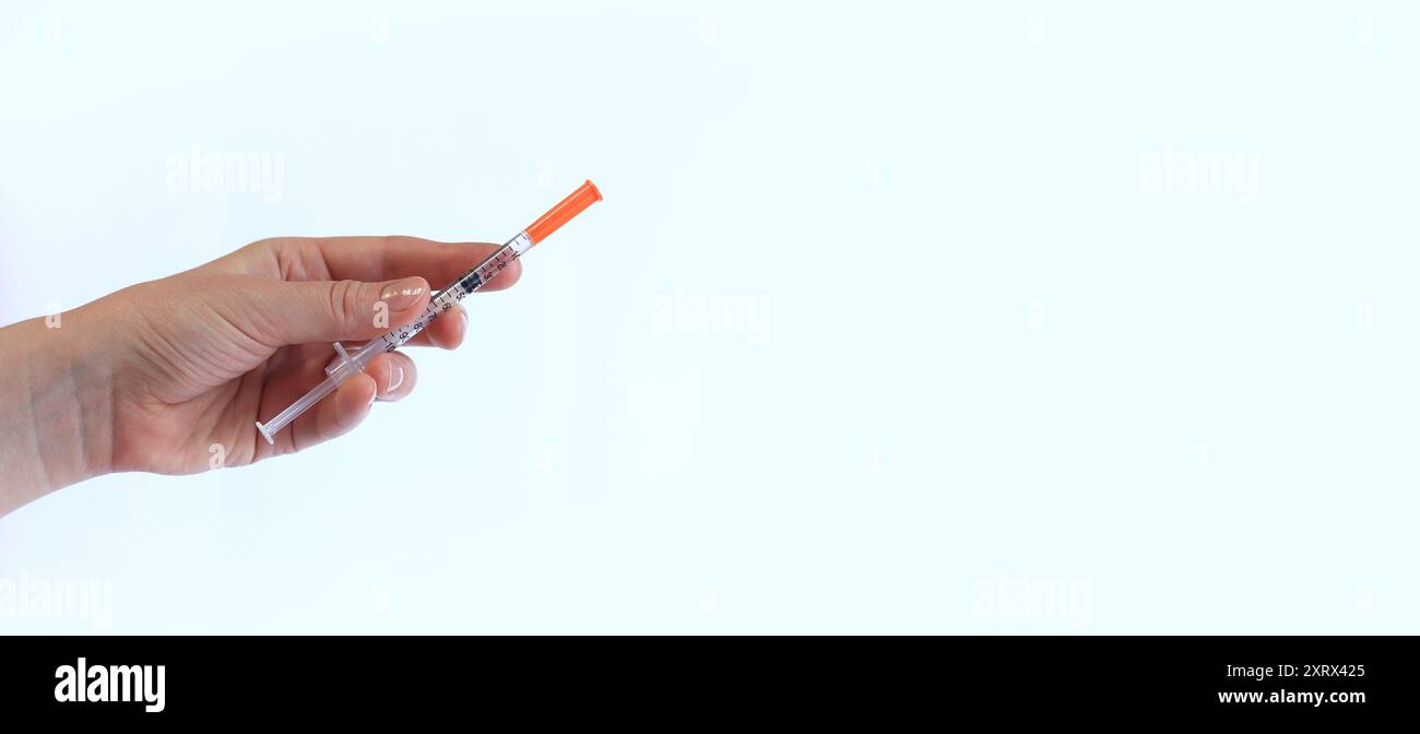 Insulin syringe. A woman's hand holds a syringe on a white background ...