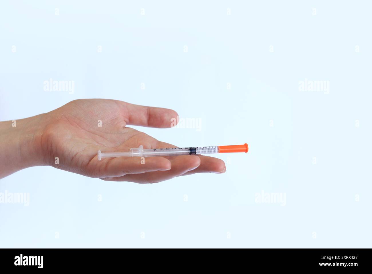 Insulin syringe. A woman's hand holds a syringe on a white background ...