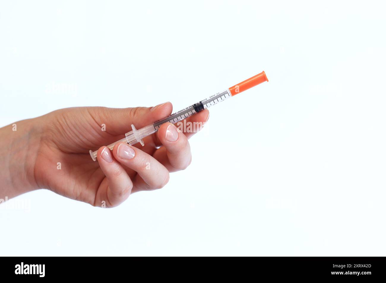 Insulin syringe. A woman's hand holds a syringe on a white background ...