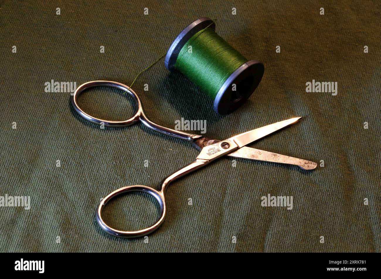 Sewing scissors and reel of green cotton Stock Photo - Alamy