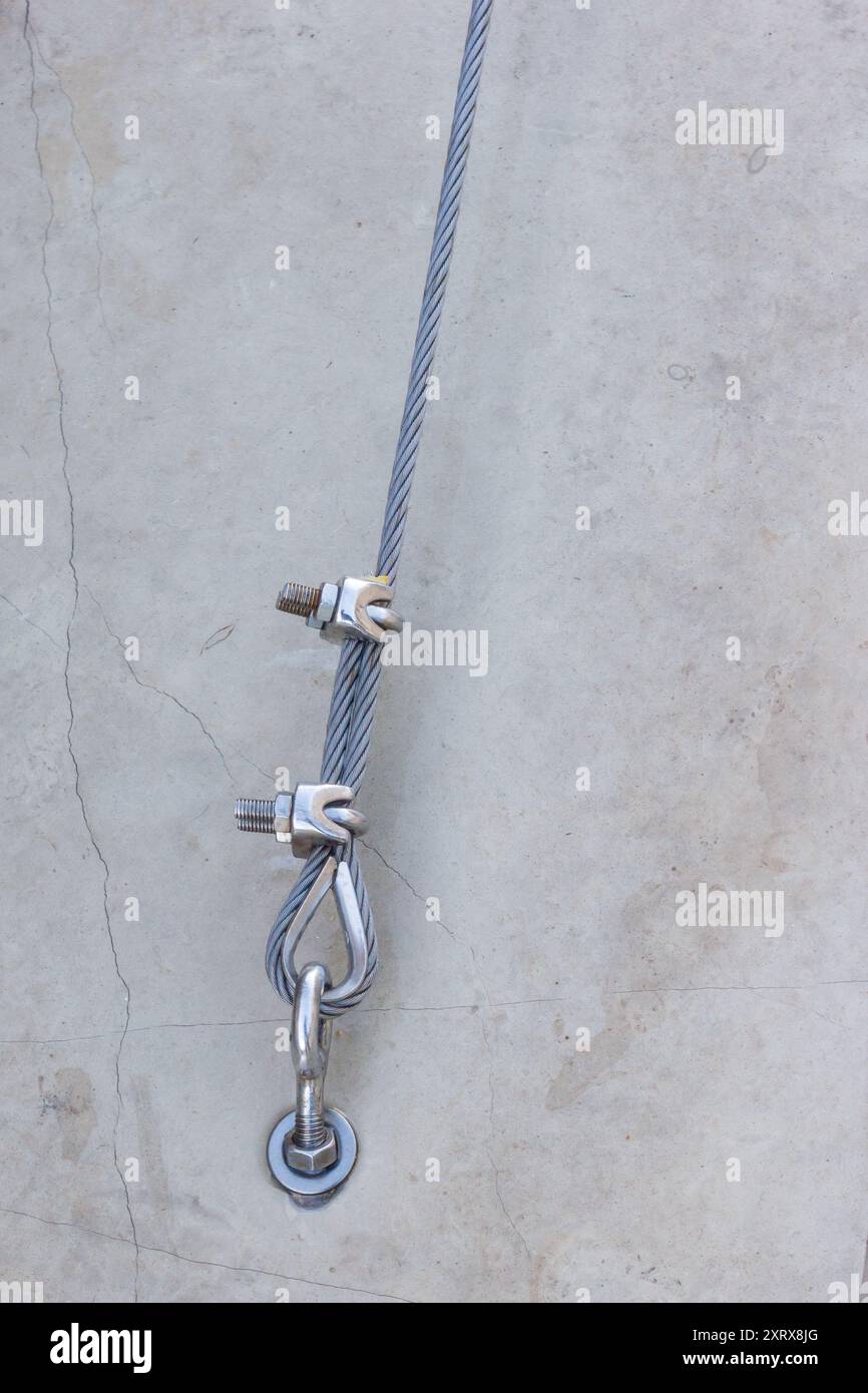 old metal wire rope tightened to a wall with clamp locks Stock Photo ...