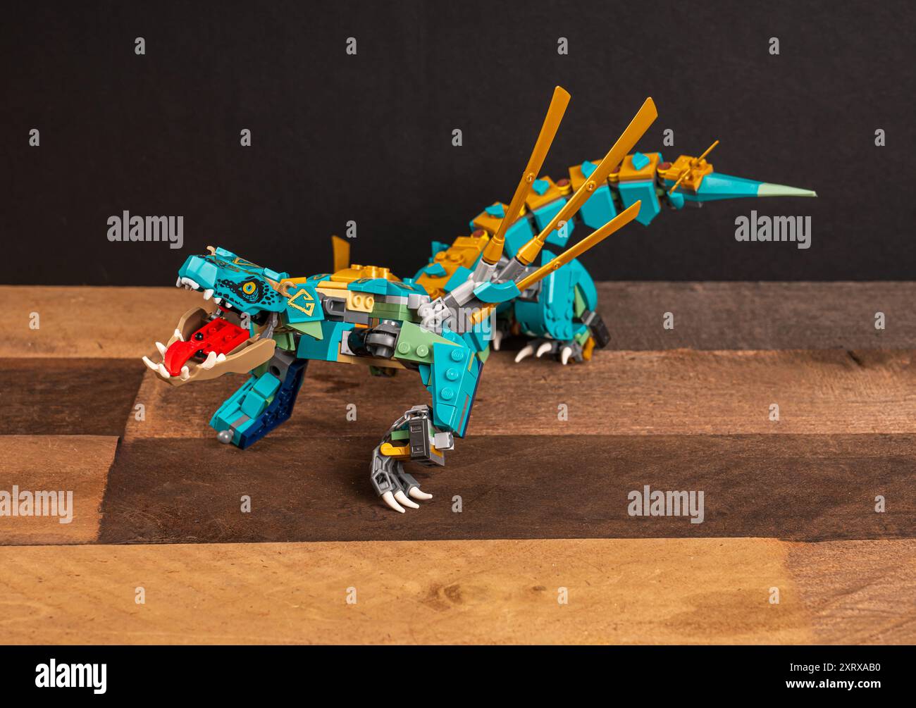 Colorful toy monster on rough wood plank table against black background ...