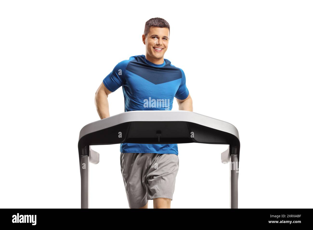 Portrait of a young man running on a treadmill and smiling at the ...