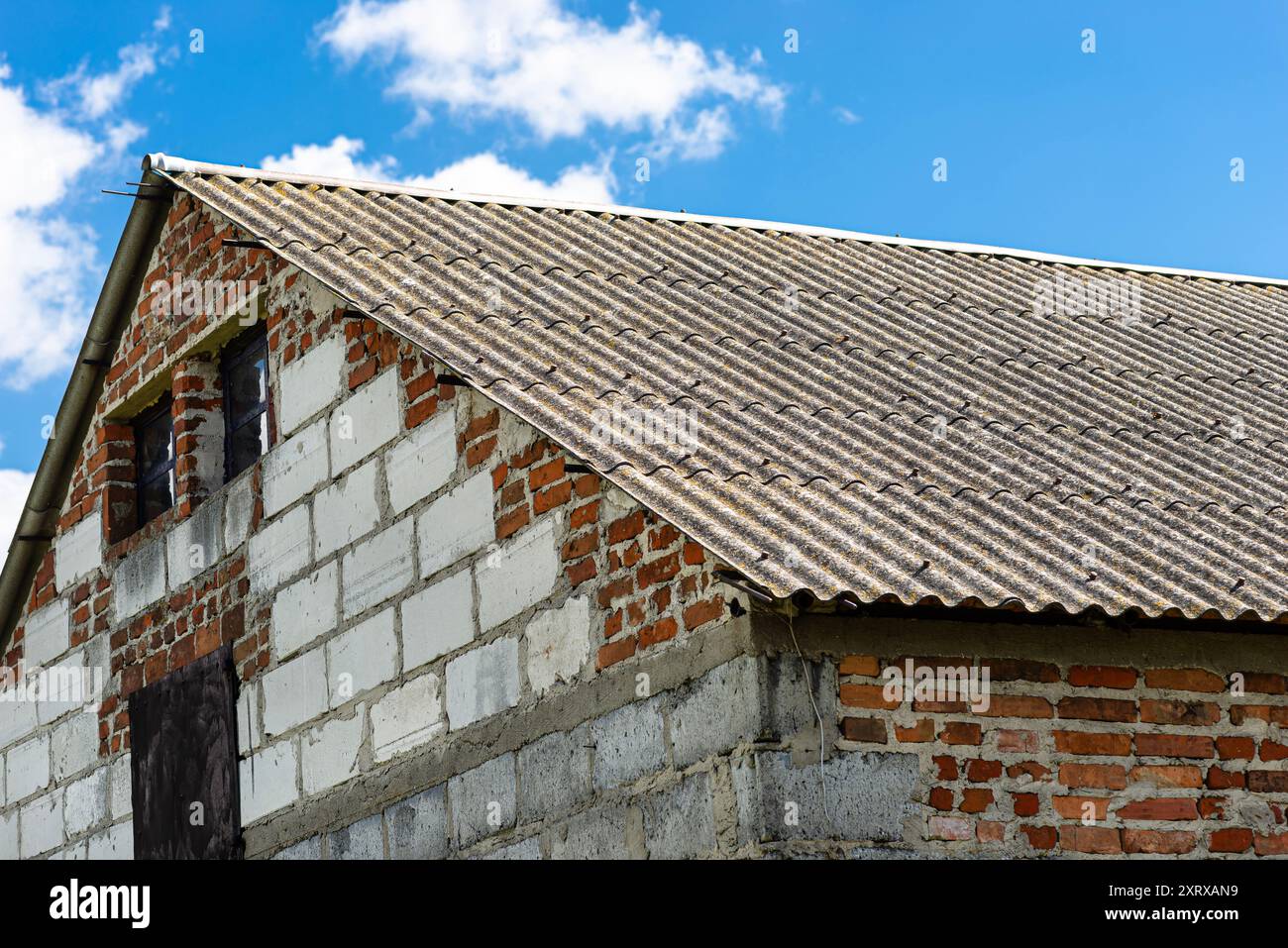 An old brick barn in the Polish countryside with a corrugated asbestos ...
