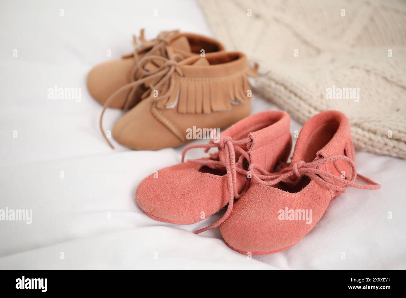 Twins concept. Two pairs of baby shoes on bed, closeup Stock Photo - Alamy