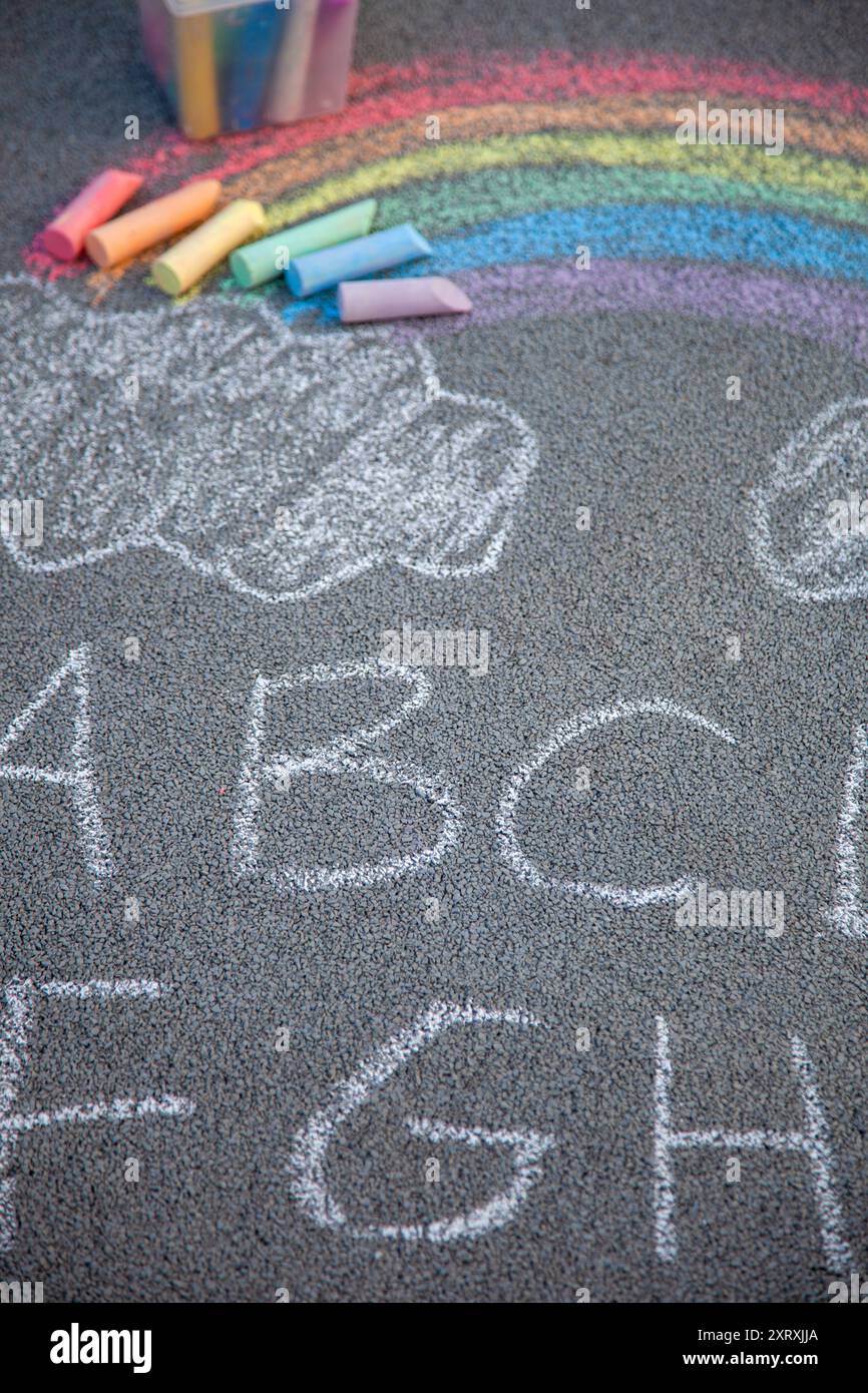 Children draw a rainbow on the asphalt with colored chalk. Sidewalk ...