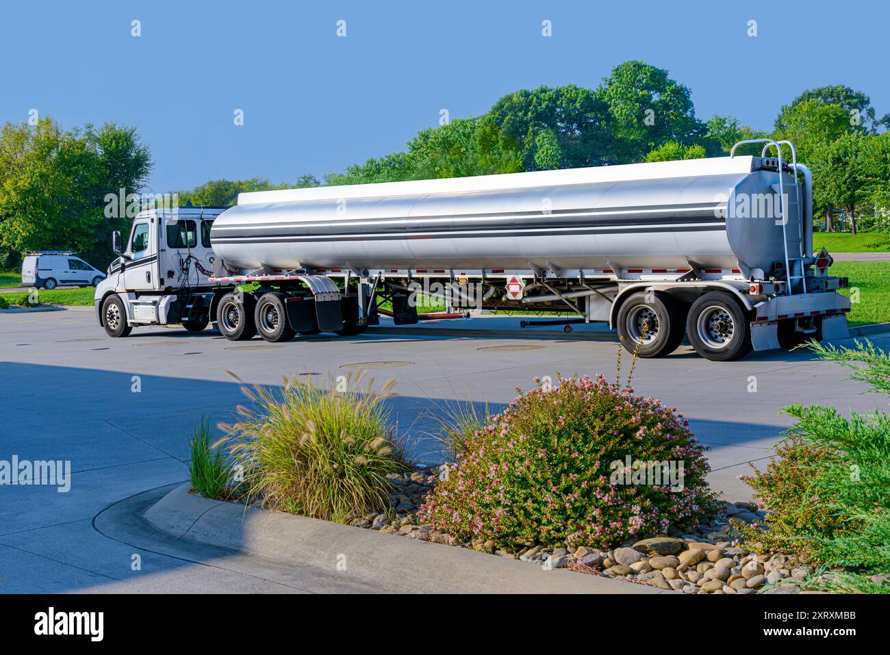 Horizontal shot of a gasoline tanker truck delivering fuel to a gas ...