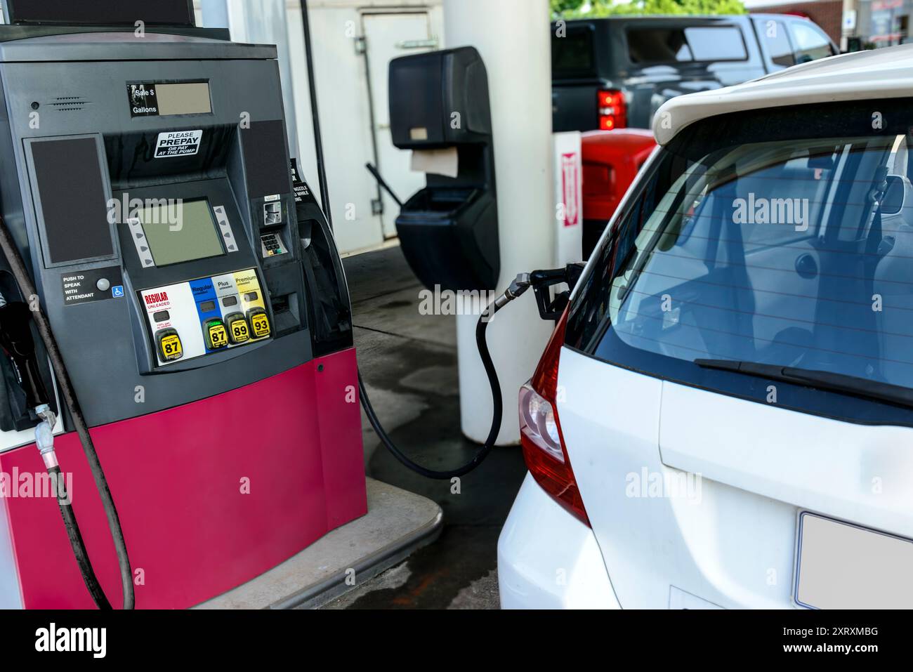 Horizontal close-up shot of a small white car getting gasoline from a ...