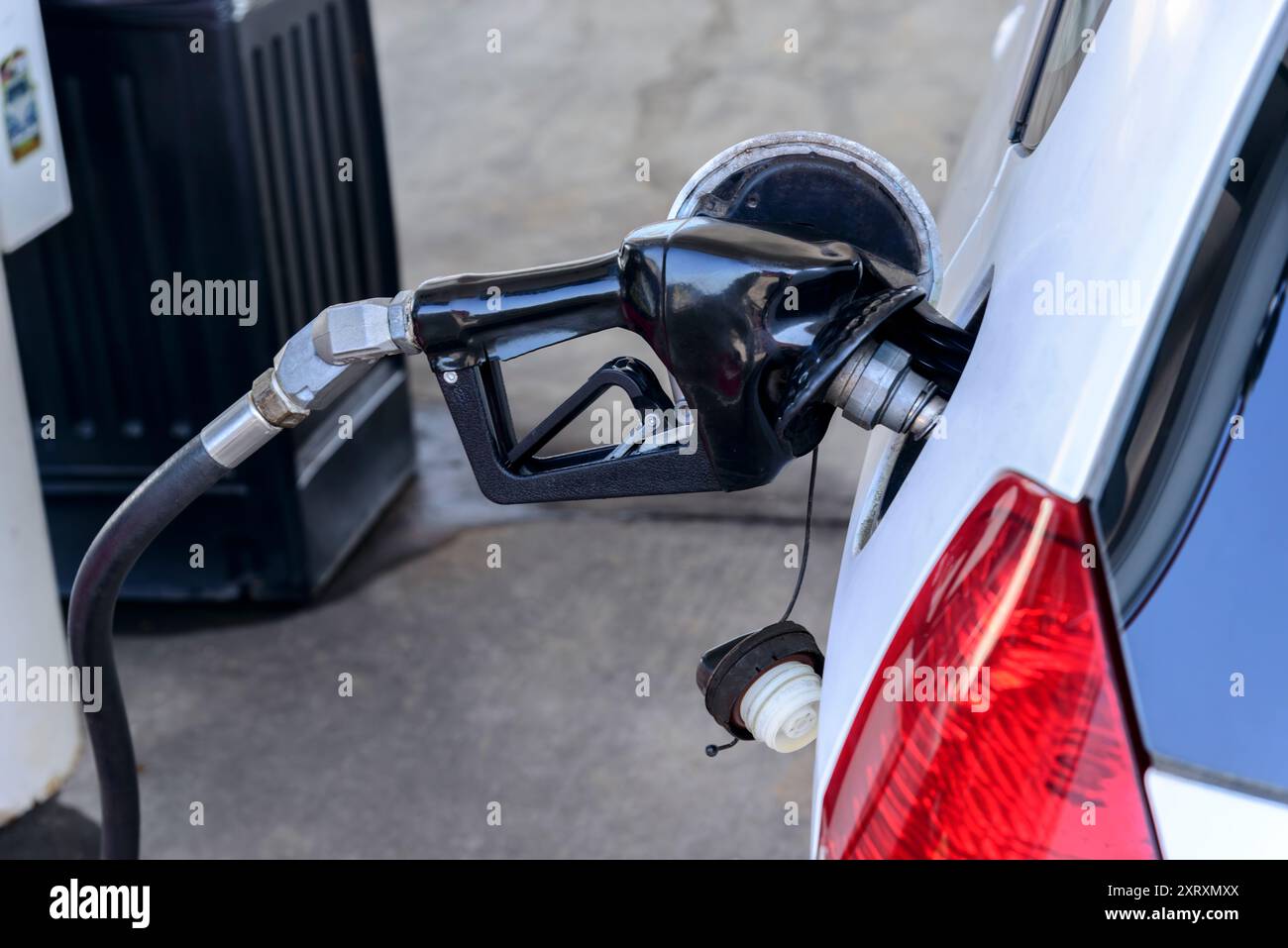 Horizontal close-up shot of a white car with a gas nozzle in the gas ...